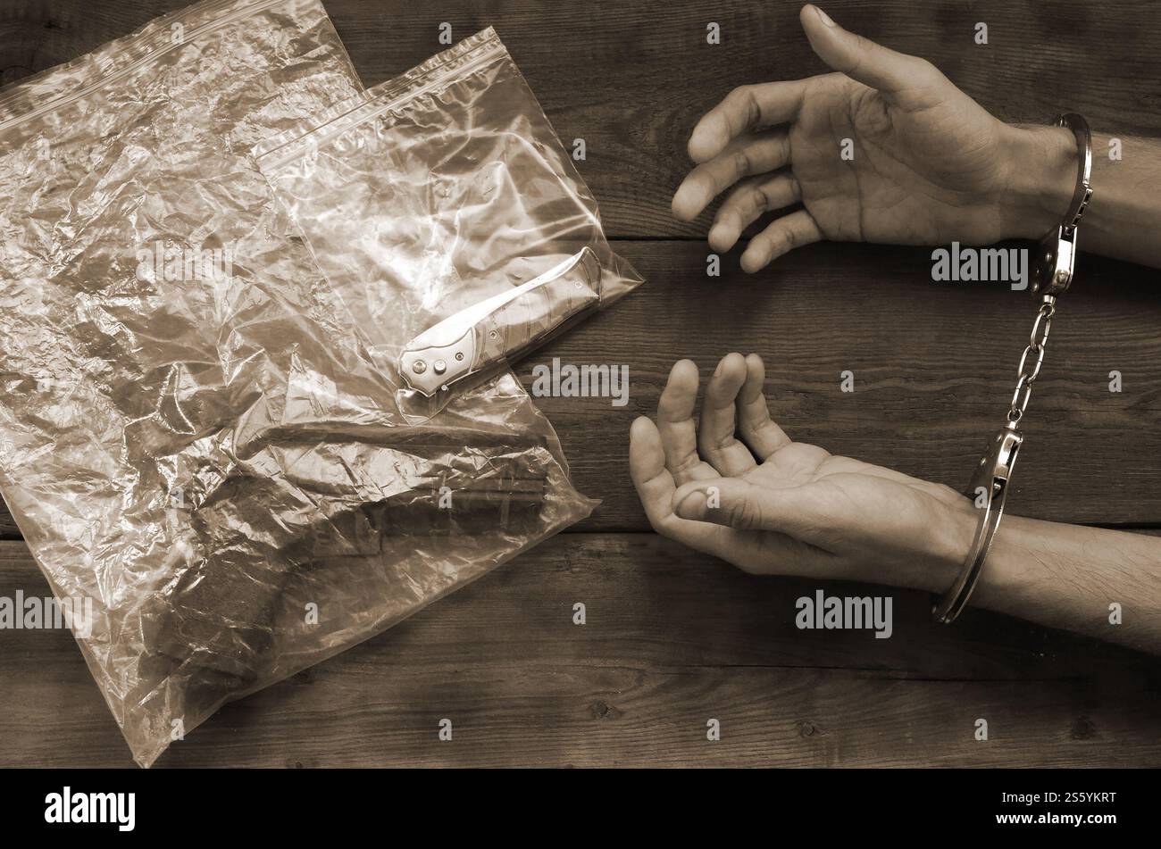 Handcuffed hands of criminal suspect on wooden table and crime scene ...