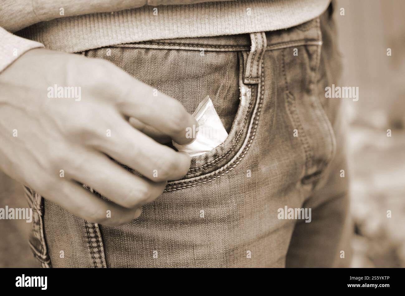 Male hand retrieving drug packet our of blue jean pocket with copy ...