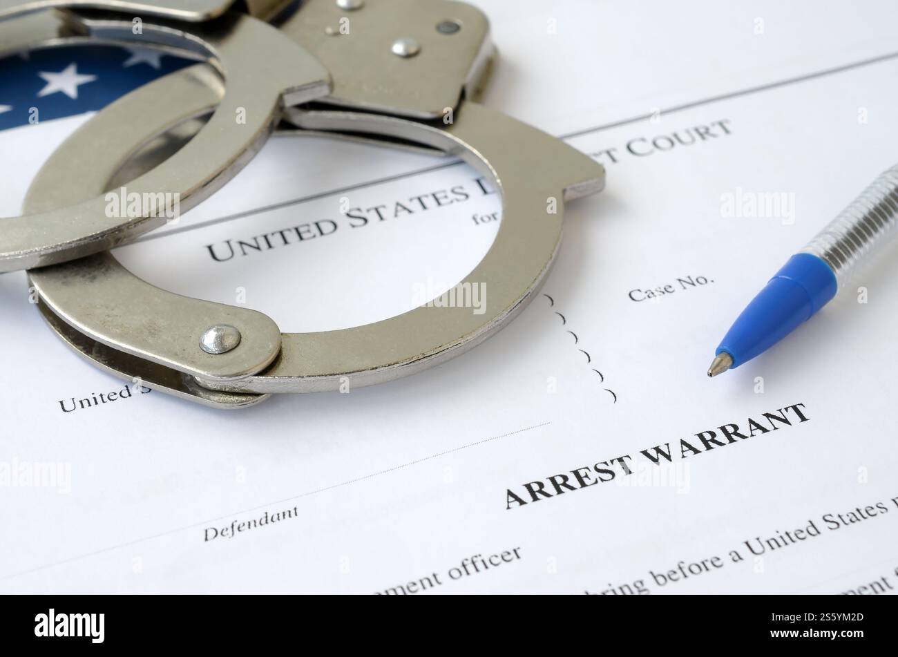 District Court Arrest Warrant court papers with handcuffs and blue pen ...