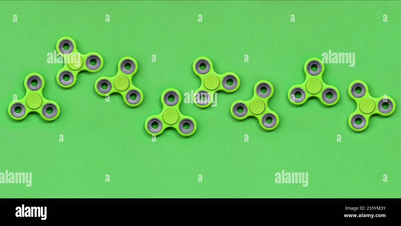 Many green fidget spinners lies on texture background of fashion pastel ...