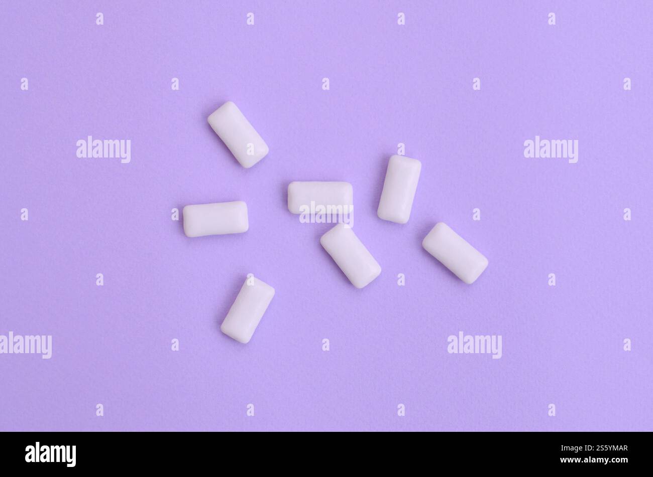 A few chewing gums lie on texture background of fashion pastel violet ...