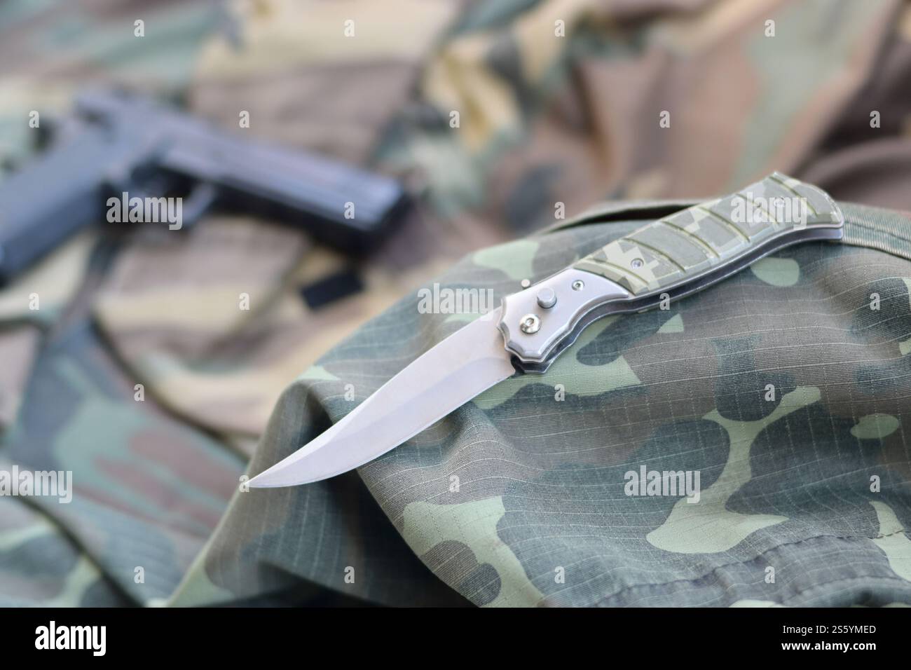 Tactical knife and pistol lie on camouflage green fabric. A set special ...