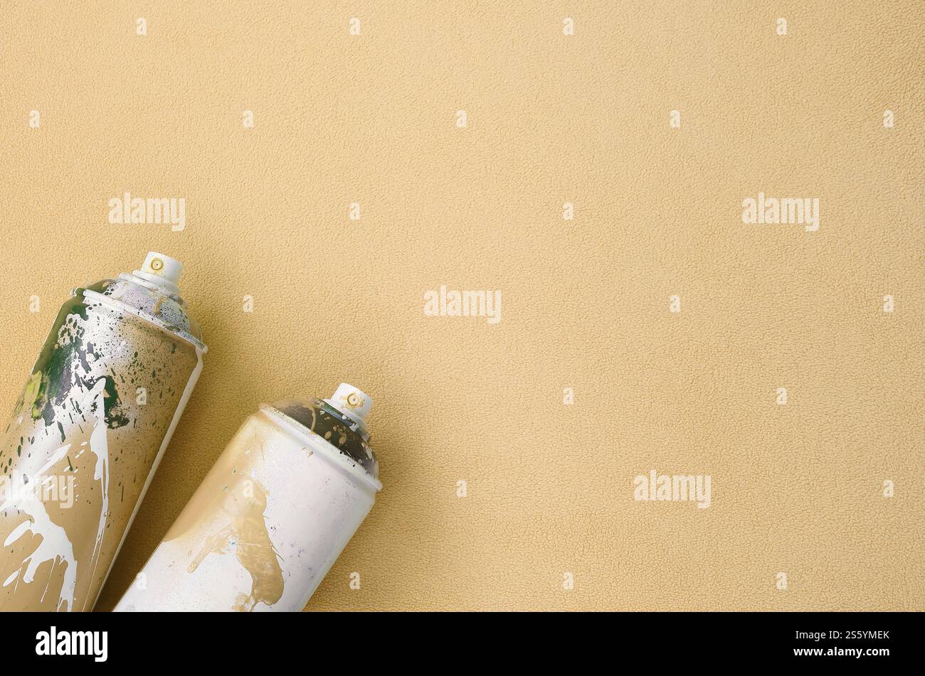 Some used blue aerosol spray cans with paint drips lies on a blanket of ...