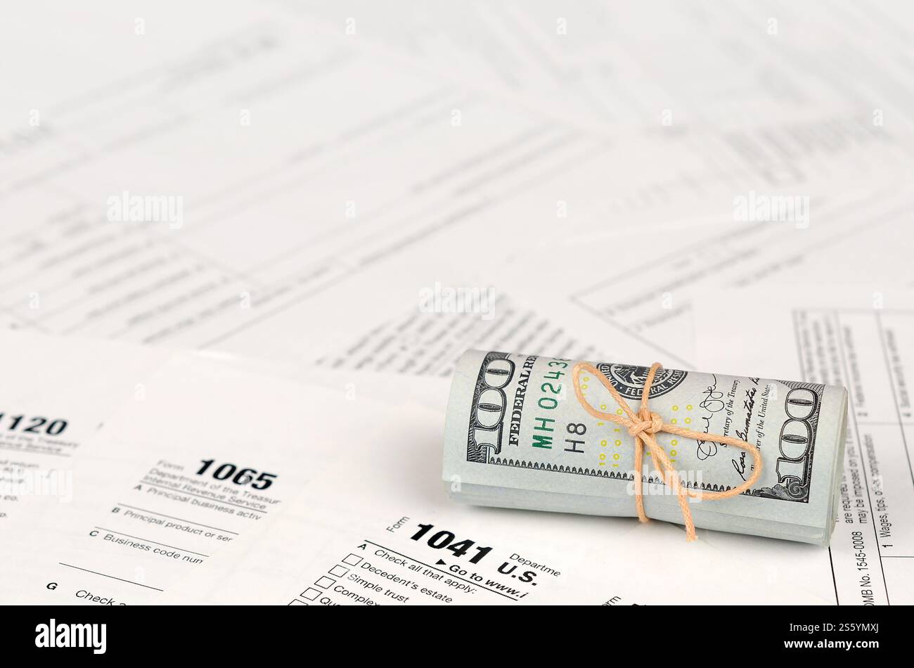 Tax forms lies near roll of hundred dollar bills. Income tax return ...