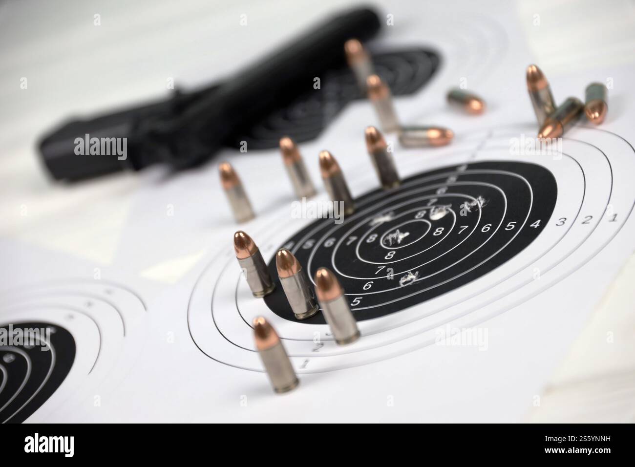 Gun and many bullets shooting targets on white table in shooting range ...