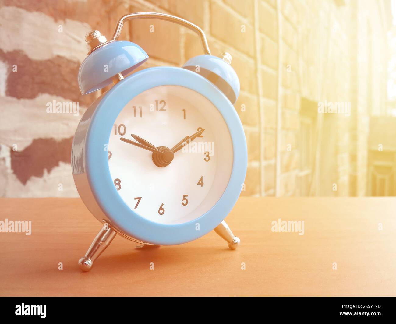 Small blue alarm clock on red building brick wall background in morning ...