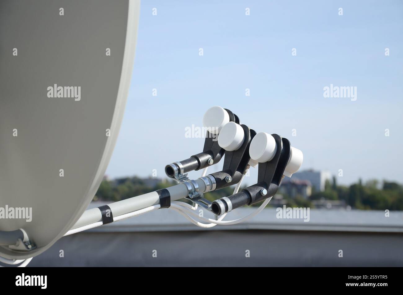 White satellite dish with three converters mounted on residental ...