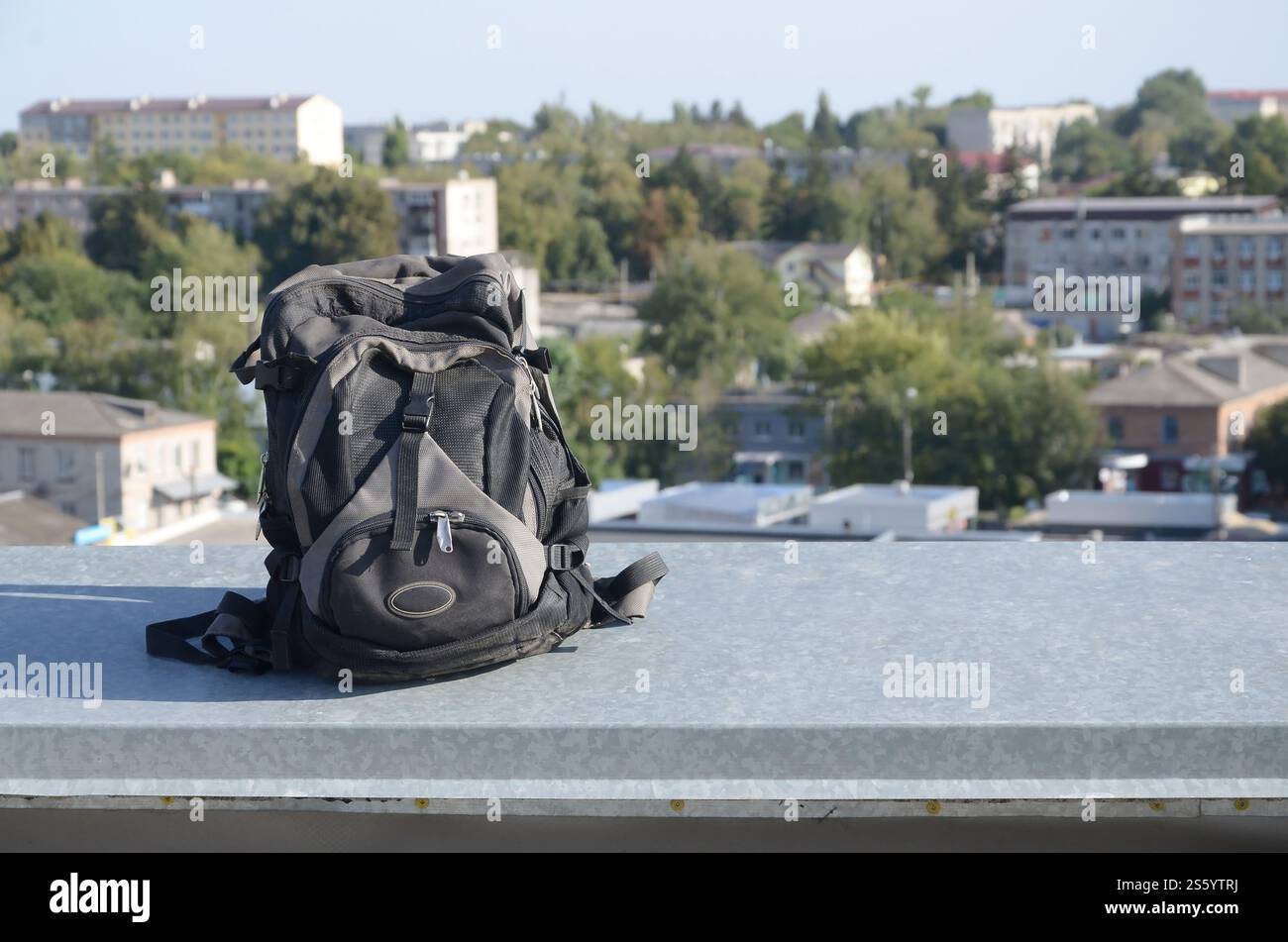 Black backpack lies on metal border of residental multistorey building ...
