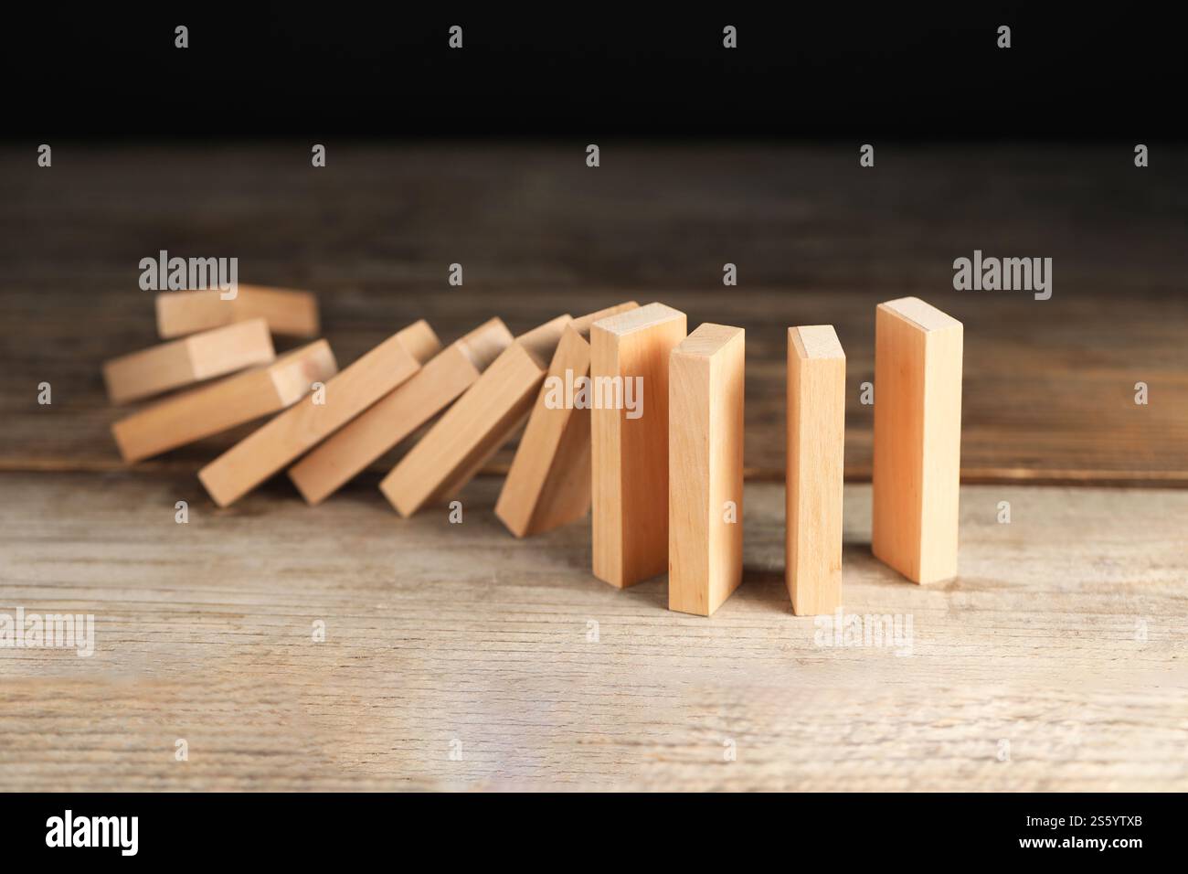 Domino effect. Wooden blocks falling on table Stock Photo - Alamy