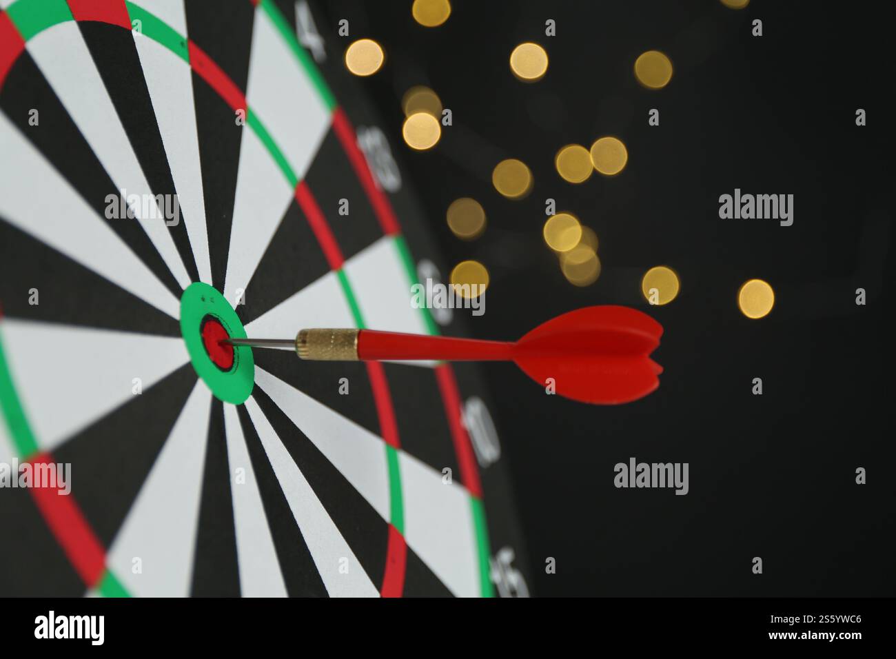 Red arrow hitting target on dart board against black background with ...