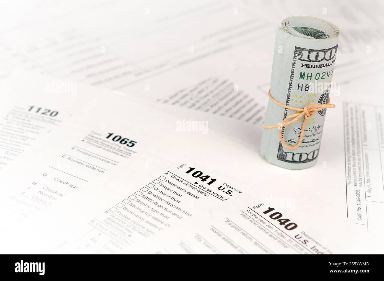 Tax forms lies near roll of hundred dollar bills. Income tax return ...