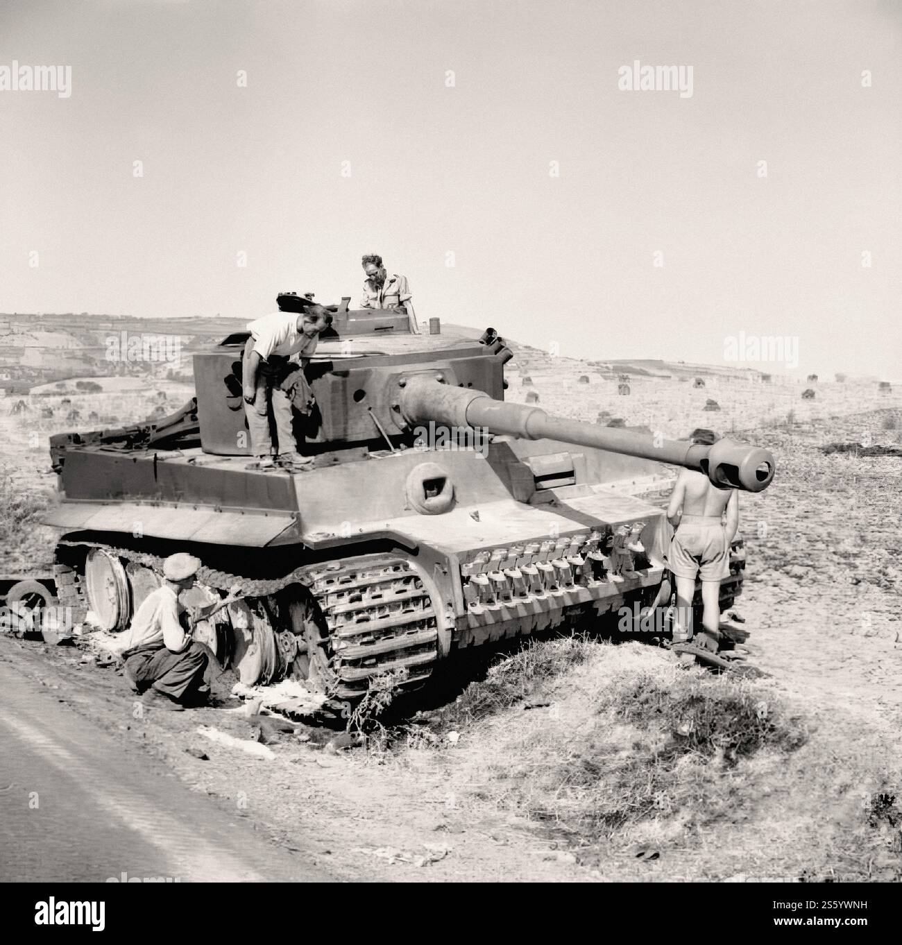 British troops and local civilians examine a knocked-out German PzKpfw ...