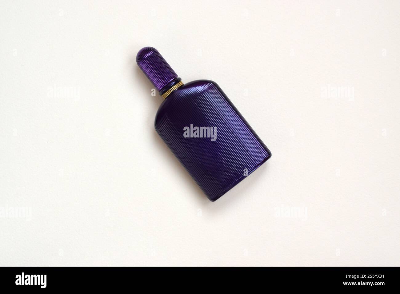 Dark purple perfume bottle with golden ribbon on pastel paper ...