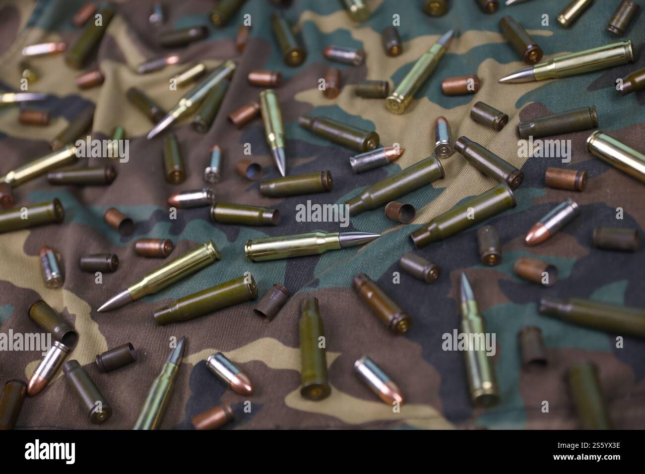 Many rifle bullets and cartridges on dark camouflage background ...