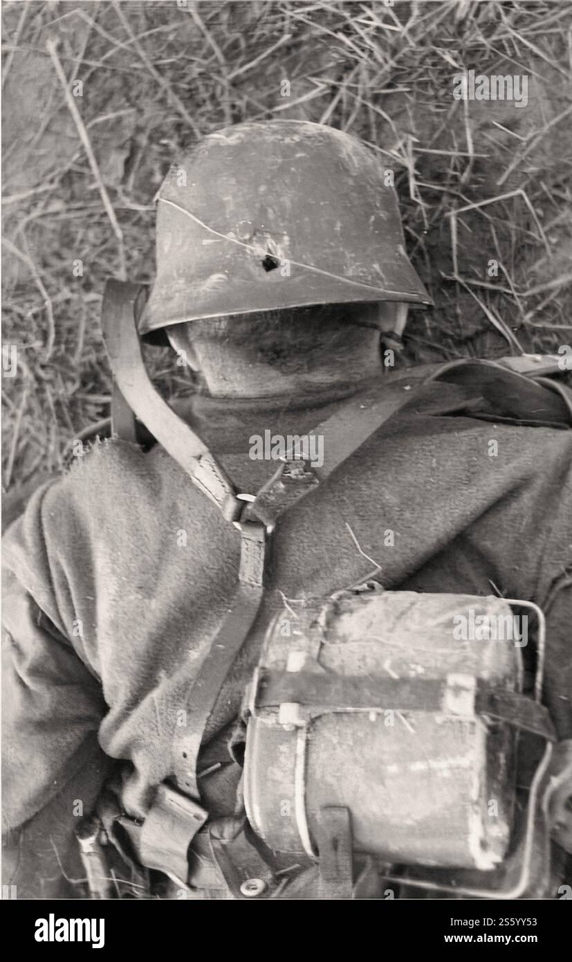 Dead German soldier lying face down on earth, bullet hole in the helmet ...