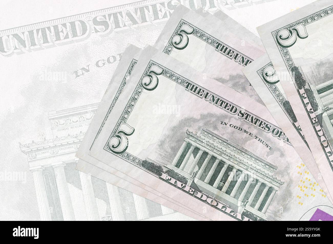 5 US dollars bills lies in stack on background of big semi-transparent ...