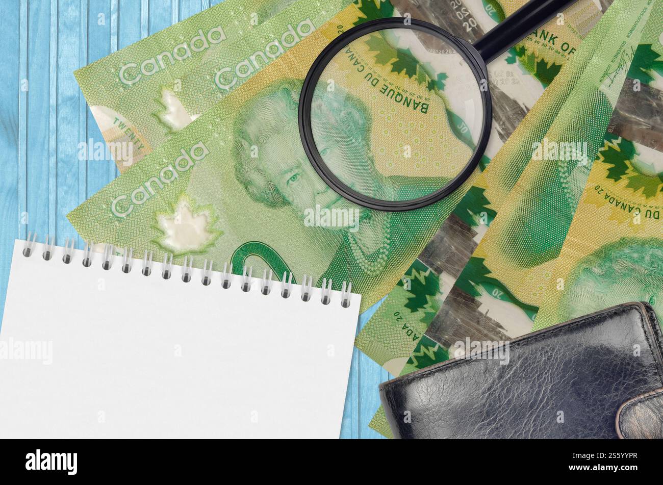 20 Canadian dollars bills and magnifying glass with black purse and ...