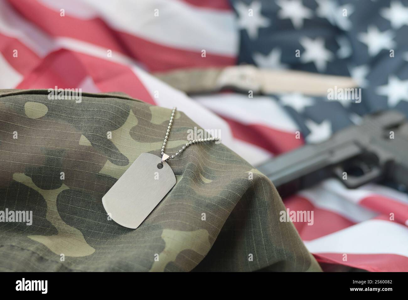 Army Dog tag token with 9mm bullets and pistol lie on folded United ...