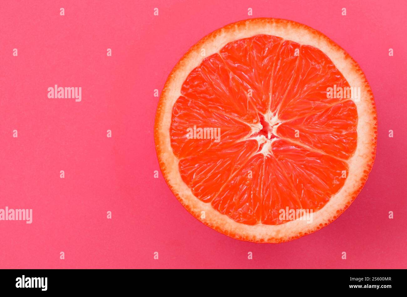 Top view of a one grapefruit slice on bright background in light pink ...