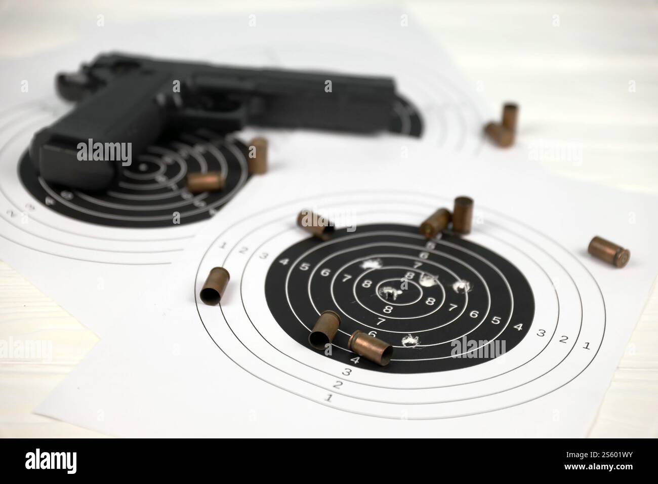 Gun and many bullets shooting targets on white table in shooting range ...