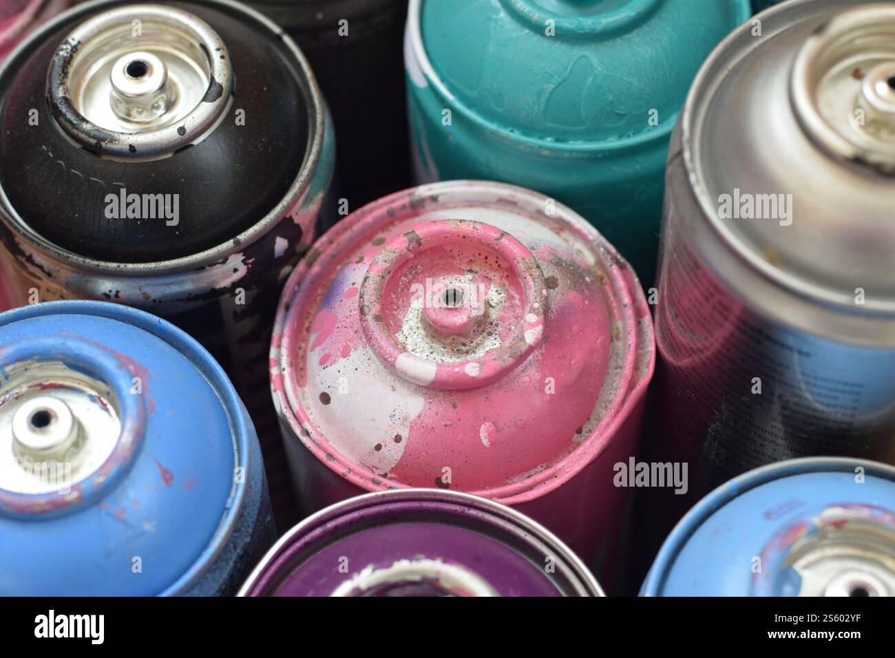 Large number of used colorful spray cans of aerosol paint lying on the ...
