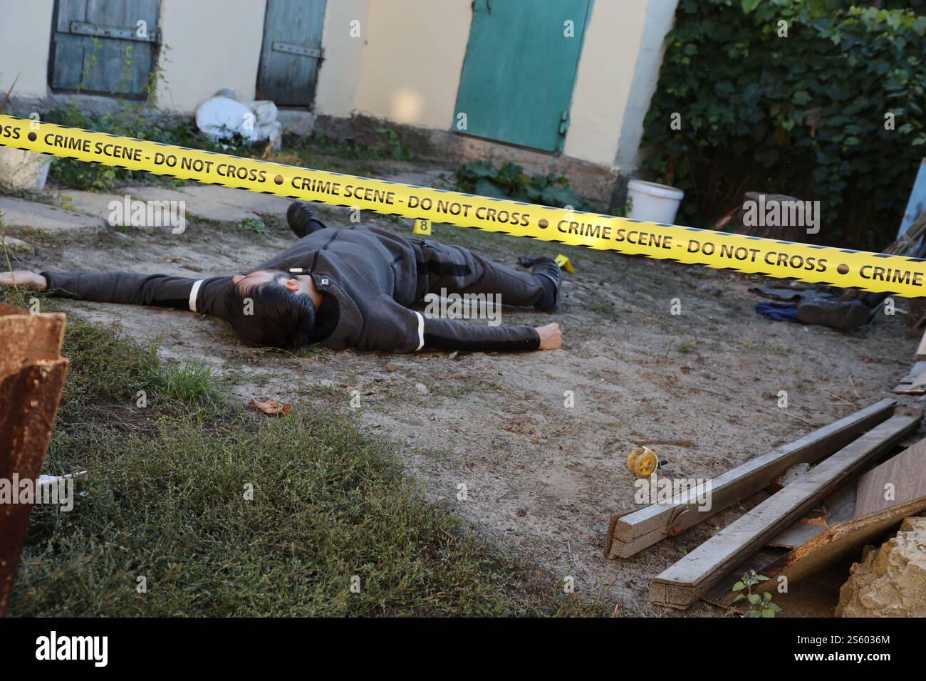 Victim of a violent crime in a backyard of residental house in evening. Dead man body under the ...