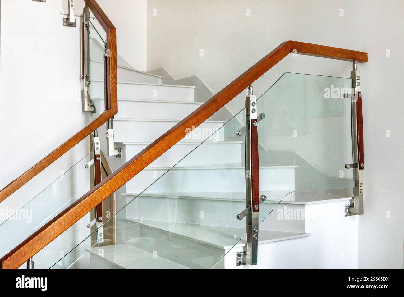 A stylish white stairway with wood and glass bannisters in a duplex ...