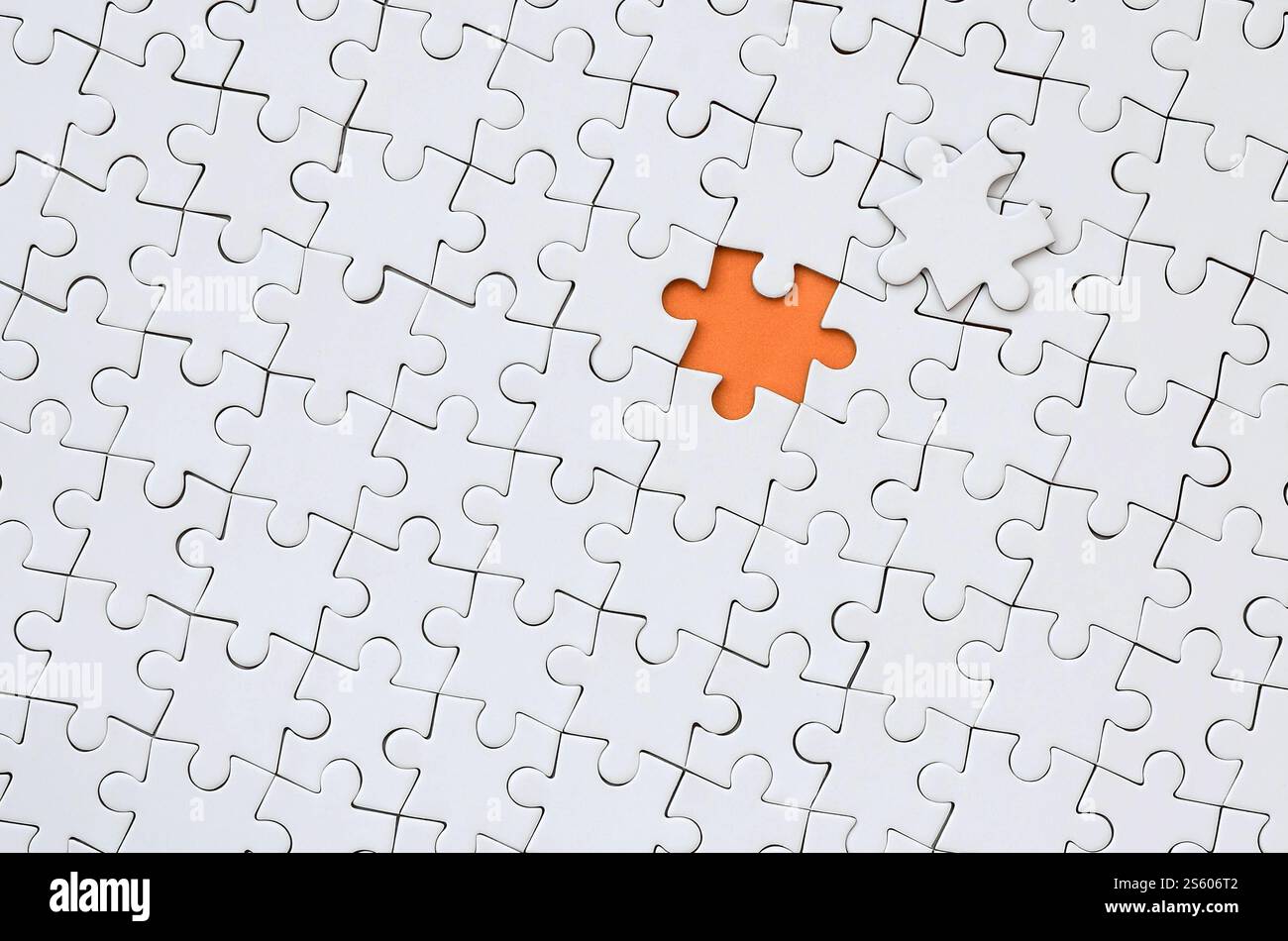 The texture of a white jigsaw puzzle in an assembled state with one ...