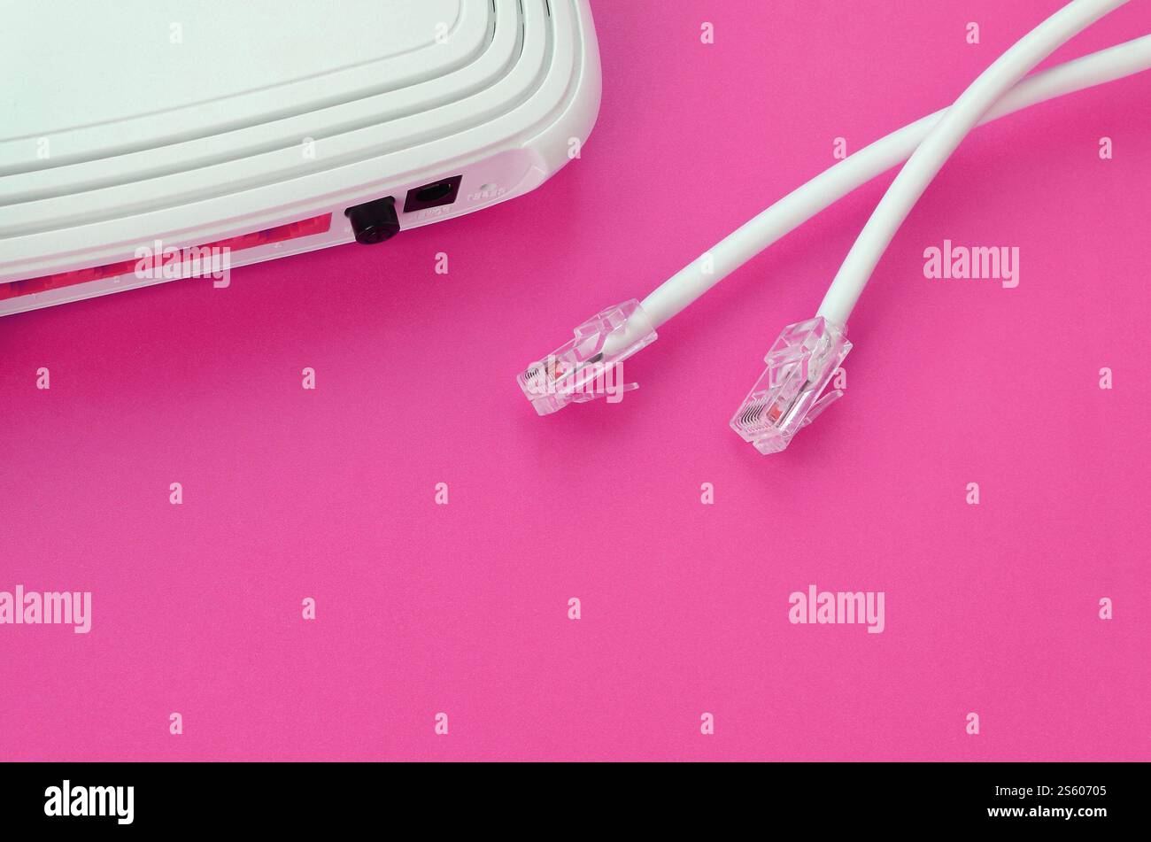 Internet router and Internet cable plugs lie on a bright pink ...