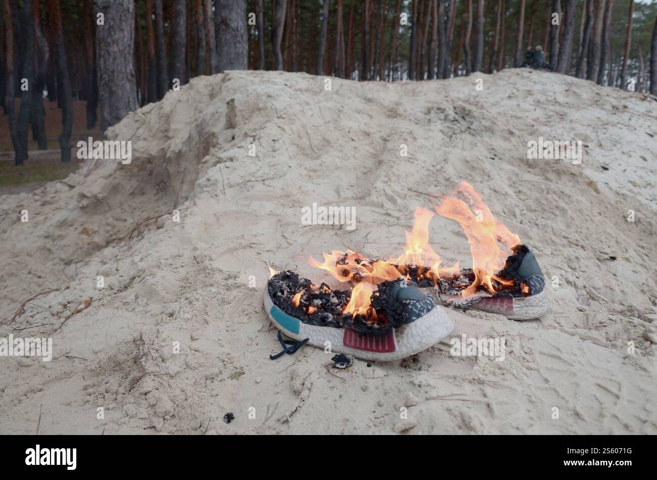 Burning sports sneakers or gym shoes on fire stand on sandy beach coast ...