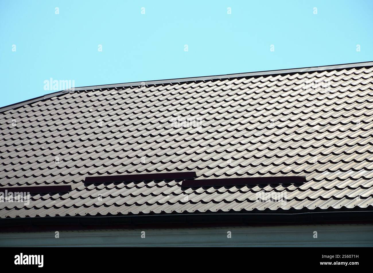 A fragment of a roof from a metal tile of dark red color. Quality ...