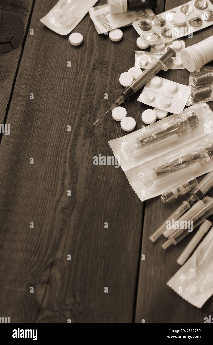 Narcotic stuff with many pills and syringes lies on wooden table and ...