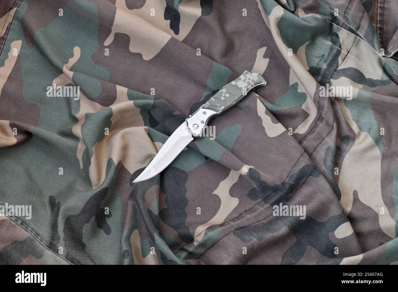Military knife on army camouflage clothes close up. Background with ...