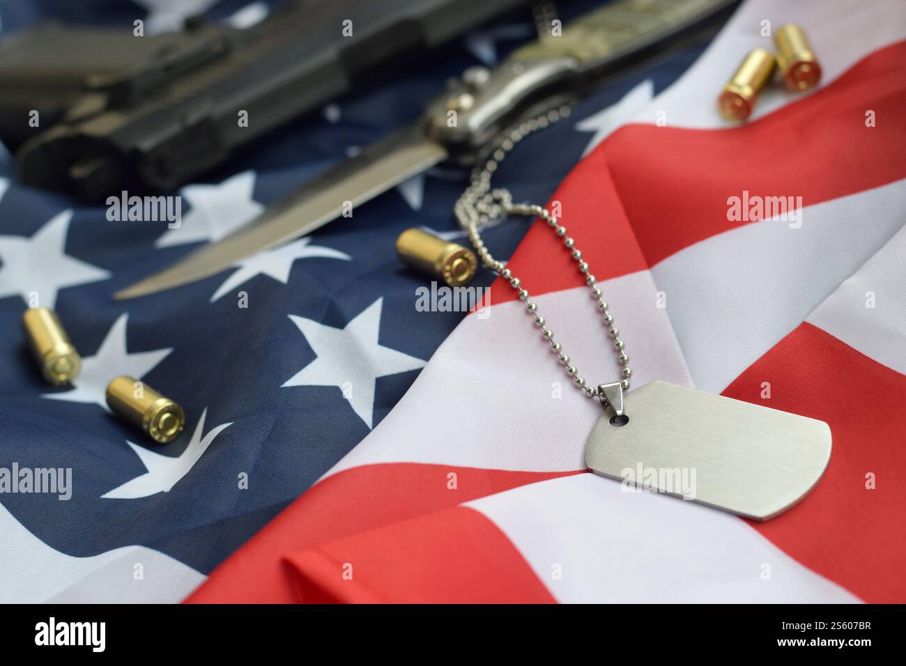 Army Dog tag token with 9mm bullets and pistol lie on folded United ...