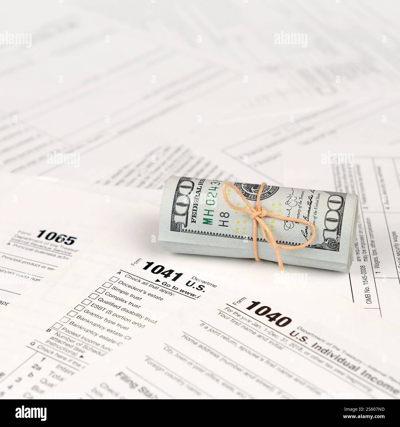 Tax forms lies near roll of hundred dollar bills. Income tax return ...