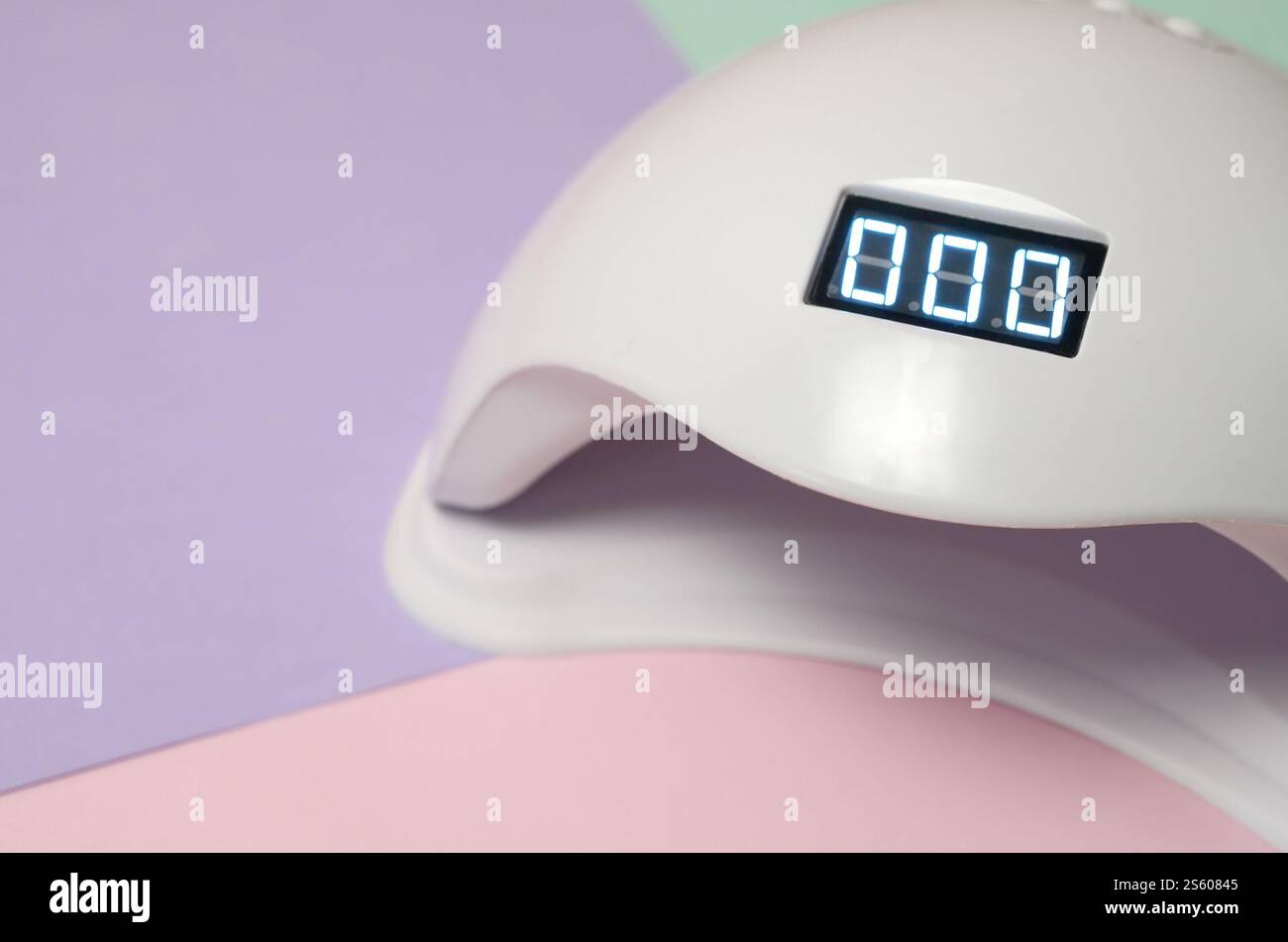 UV LED nail lamp for curing process by gel method lies on pastel multi ...
