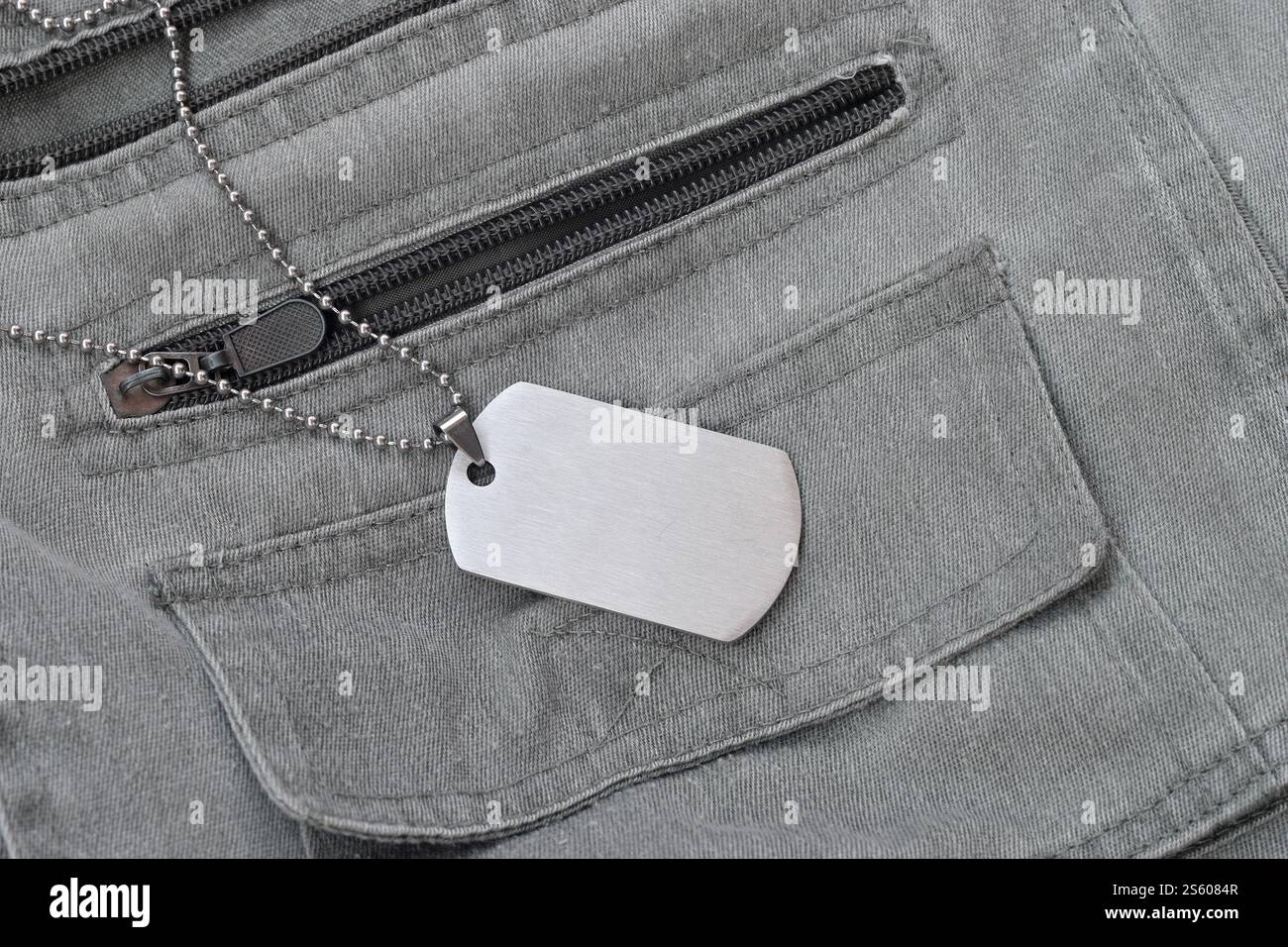 Silvery military beads with dog tag on dark grey vest with pockets ...