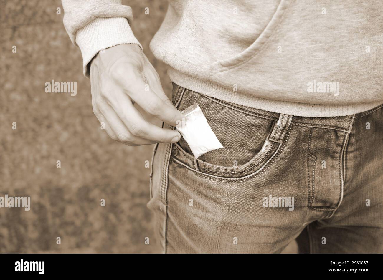 Male hand retrieving drug packet our of blue jean pocket with copy ...