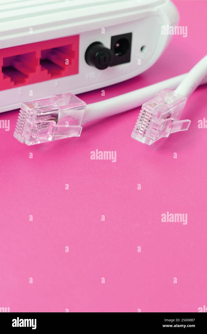Internet router and Internet cable plugs lie on a bright pink ...