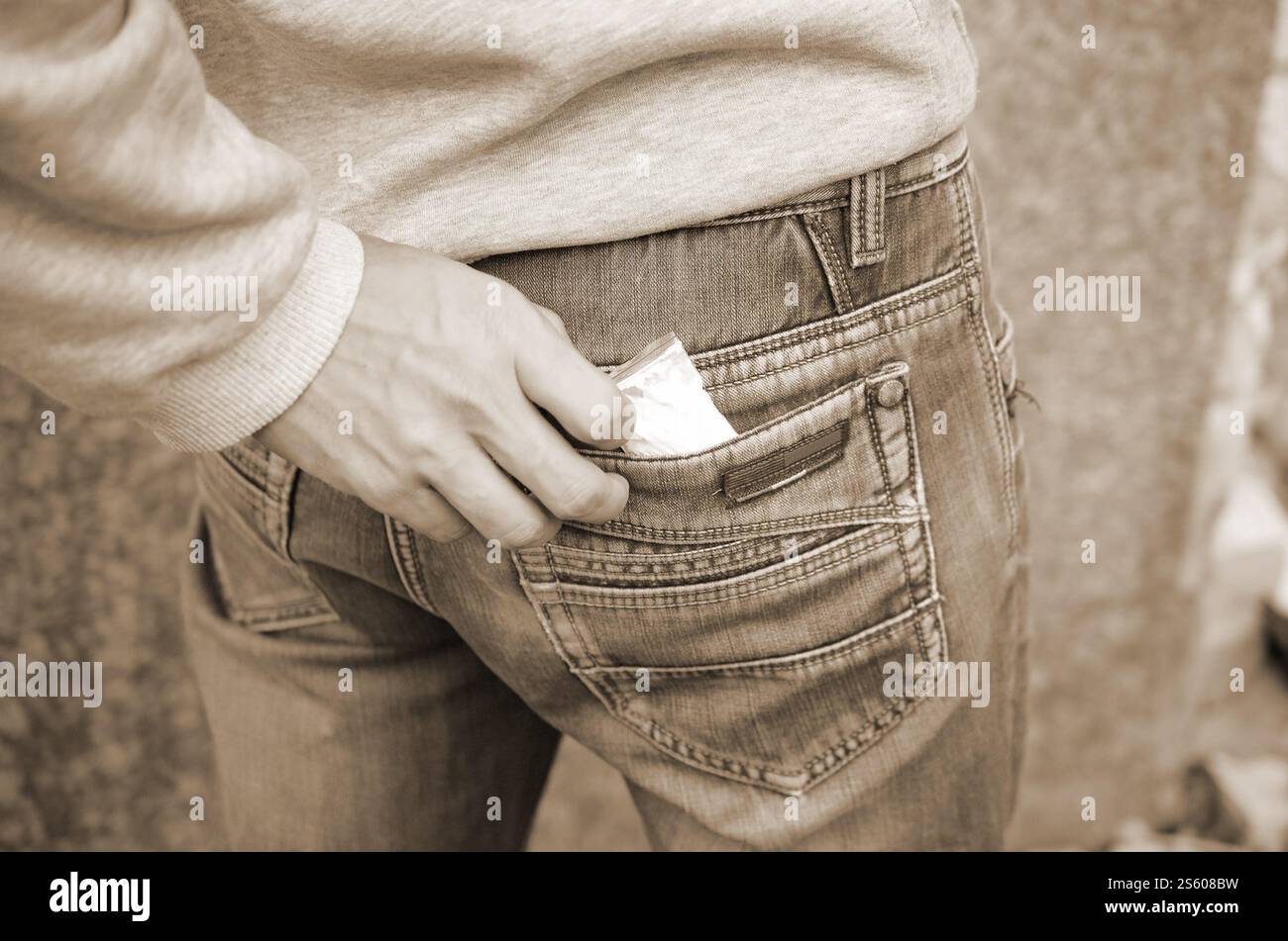 Male hand retrieving drug packet our of blue jean pocket with copy ...
