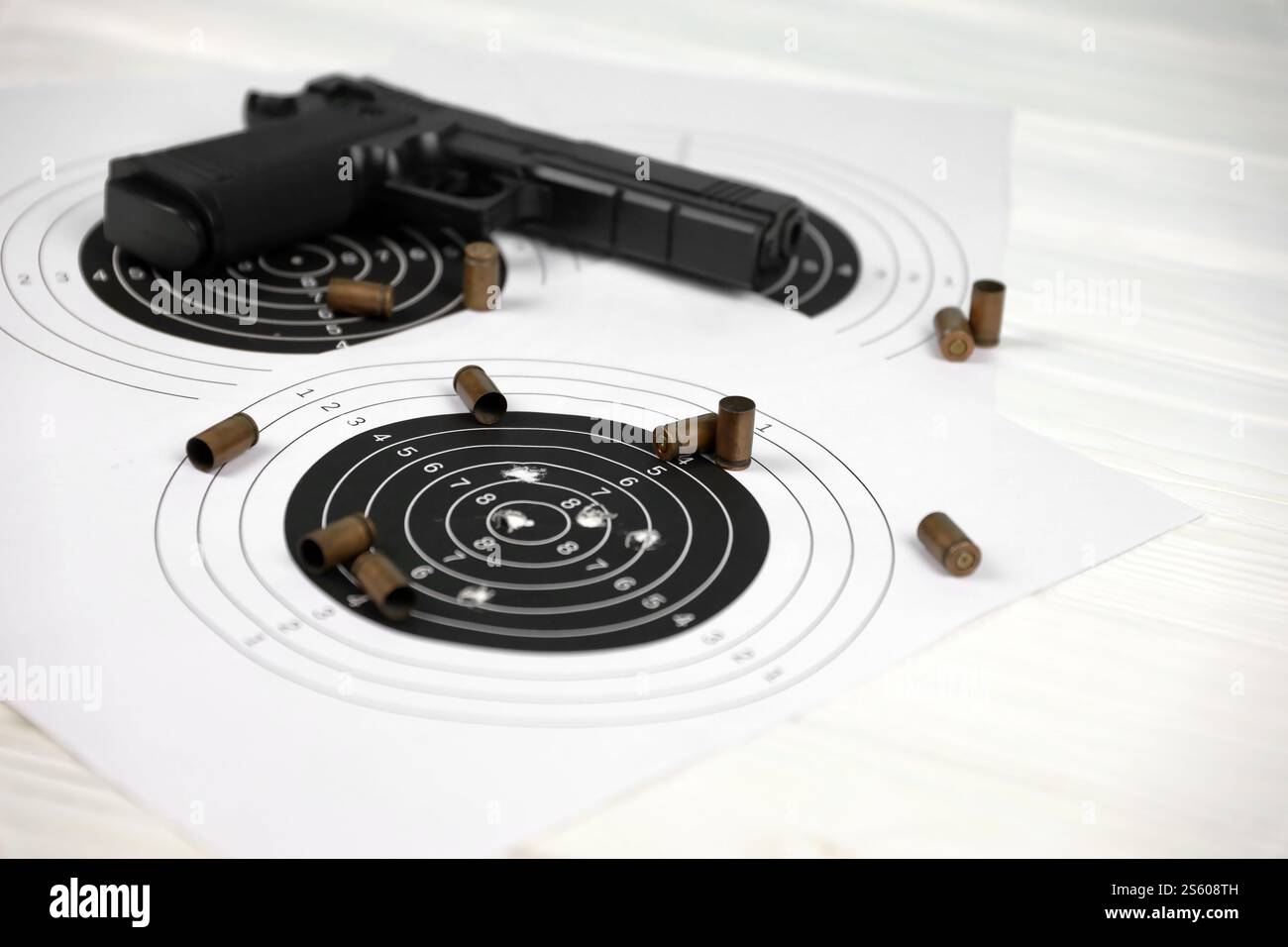 Gun and many bullets shooting targets on white table in shooting range ...