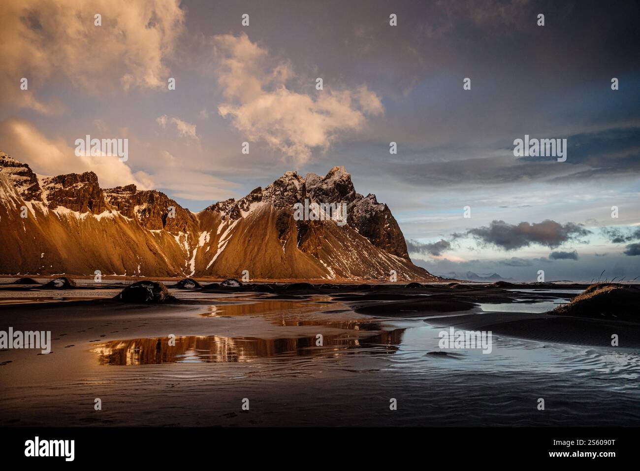 Golden hour light illuminating Vestrahorn mountain and reflections on the black sand beach in ...