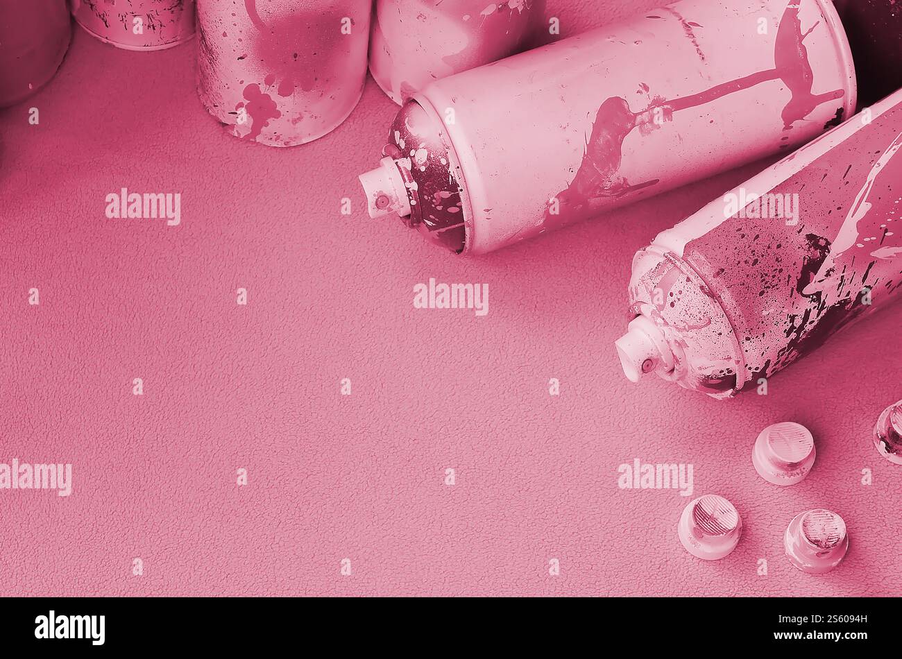 Some used pink aerosol spray cans and nozzles with paint drips lies on ...
