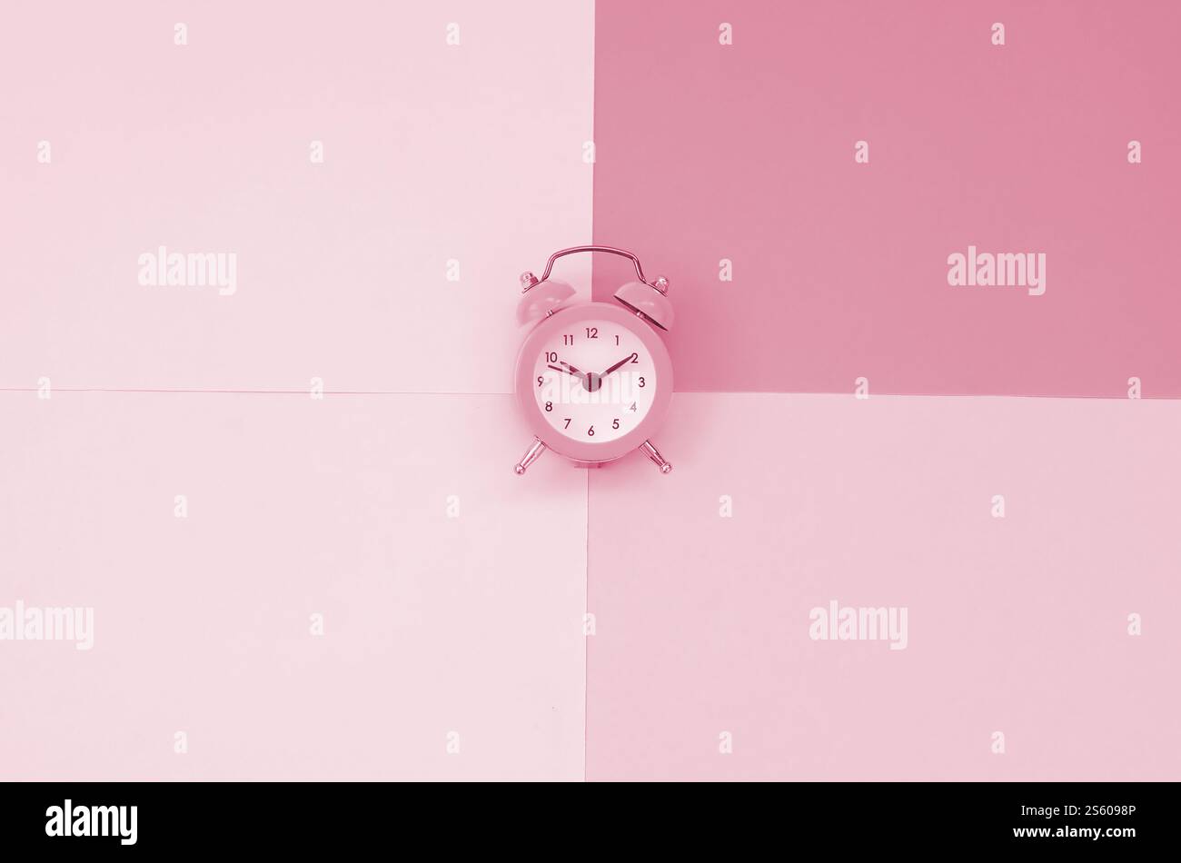 A small pink alarm clock is located between areas of different colors ...