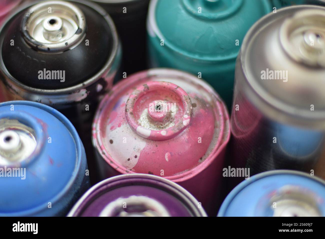 Large number of used colorful spray cans of aerosol paint lying on the ...