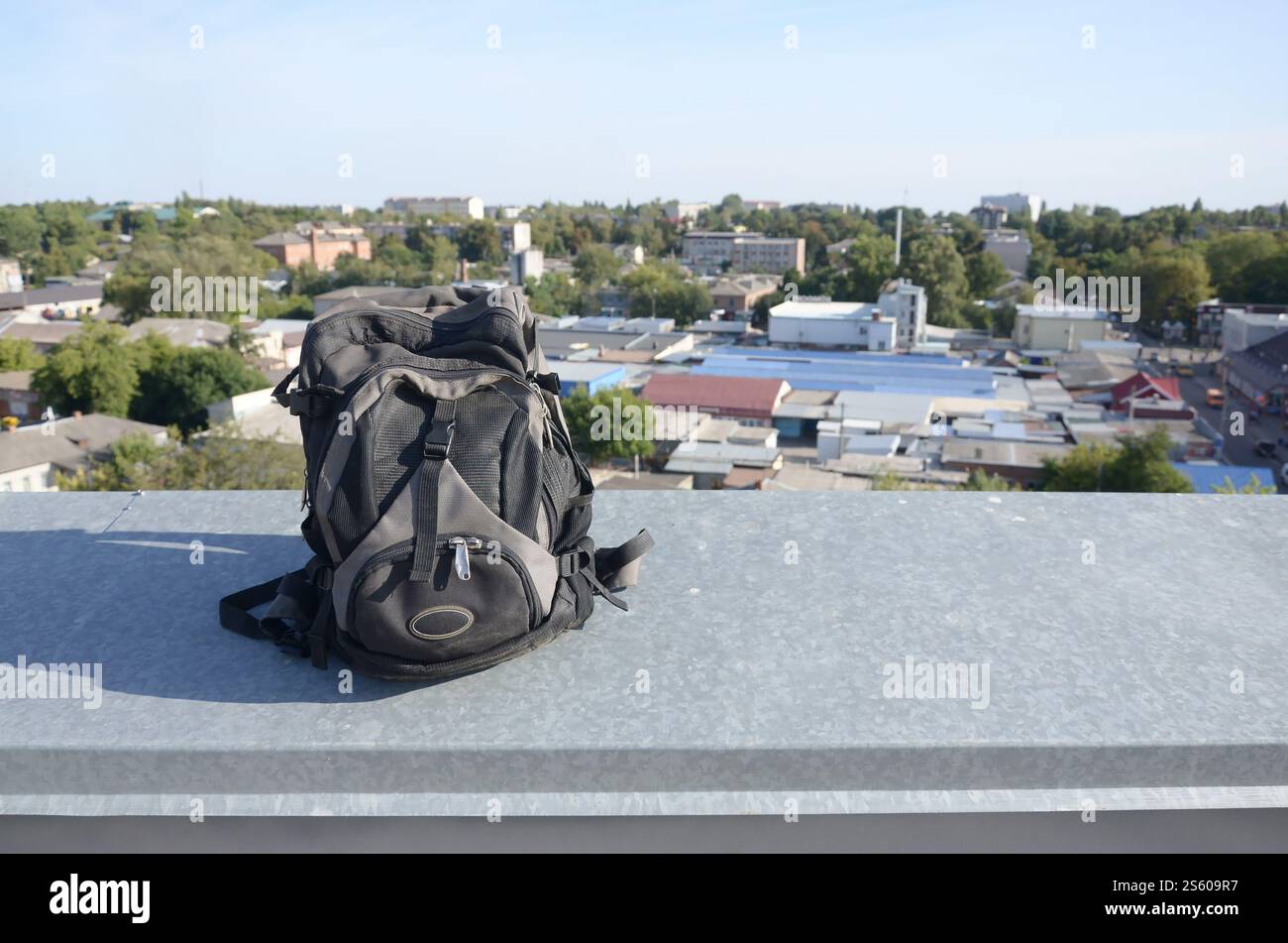 Black backpack lies on metal border of residental multistorey building ...