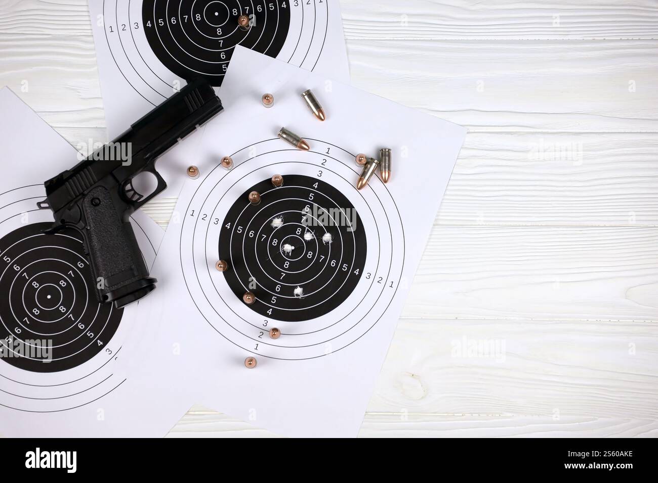 Gun and many bullets shooting targets on white table in shooting range ...
