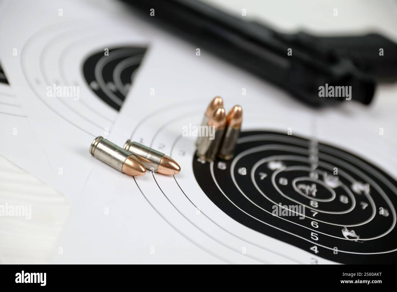 Gun and many bullets shooting targets on white table in shooting range ...