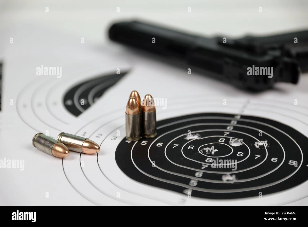 Gun and many bullets shooting targets on white table in shooting range ...