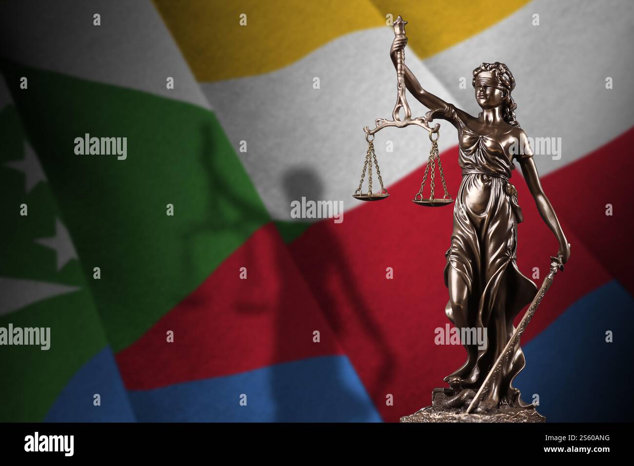 Comoros flag with statue of lady justice and judicial scales in dark ...